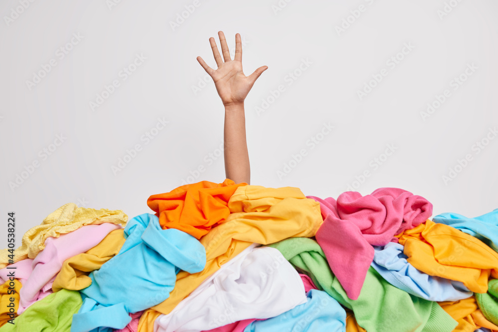 Unrecognizable human raises arm reaches out heap of colorful unfolded ...
