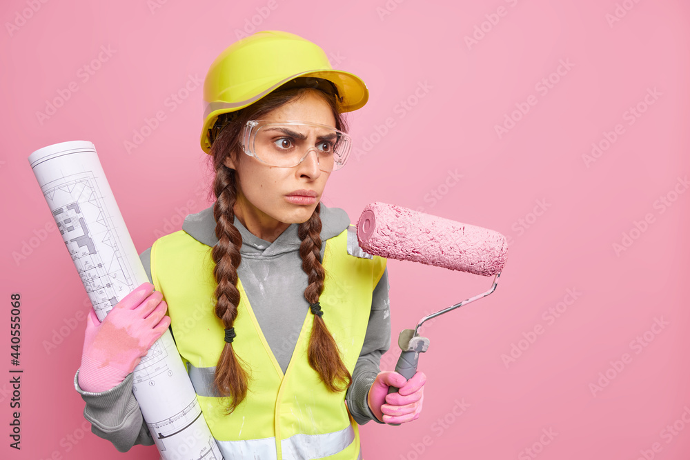 Horizontal shot of serious skilled female engineer focused away with ...