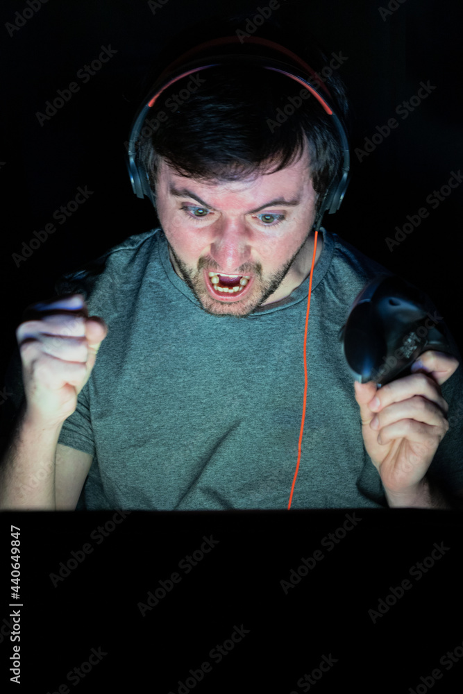 Joven enfadado jugando a un videojuego con auriculares y un mando en la ...