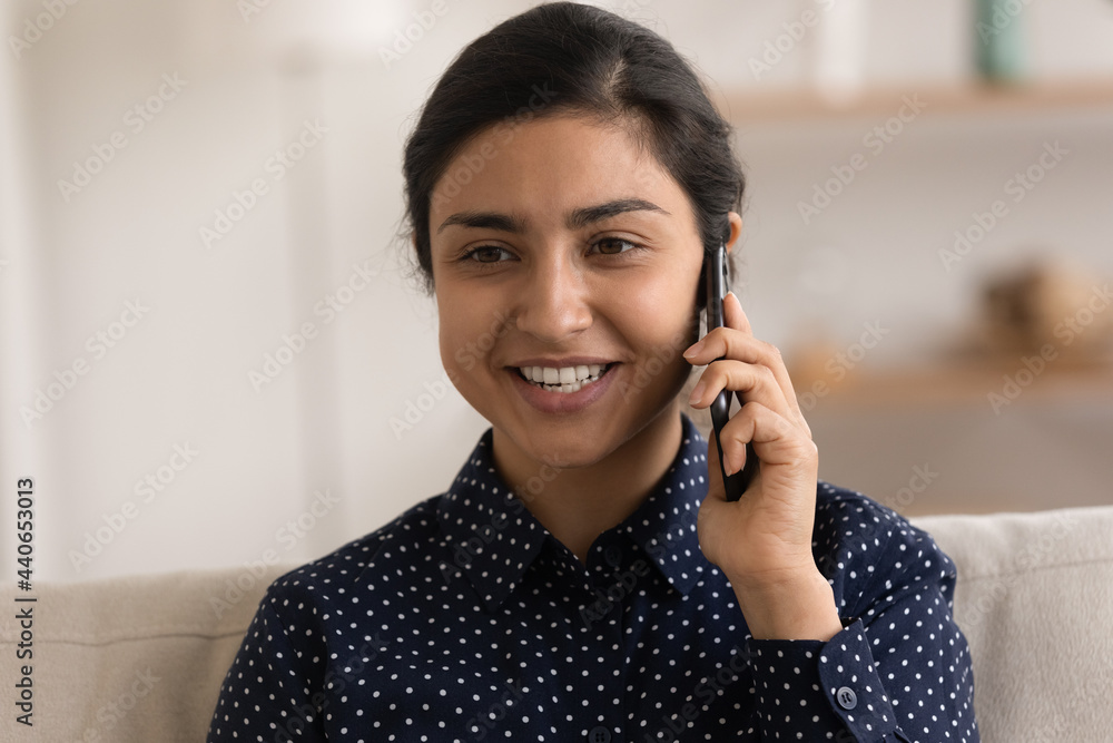 Smiling young Indian woman use modern cellphone talk speak on gadget ...