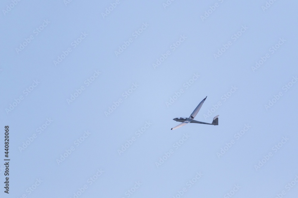 Fotka „A portrait of a glider plane flying in the distance in a light ...