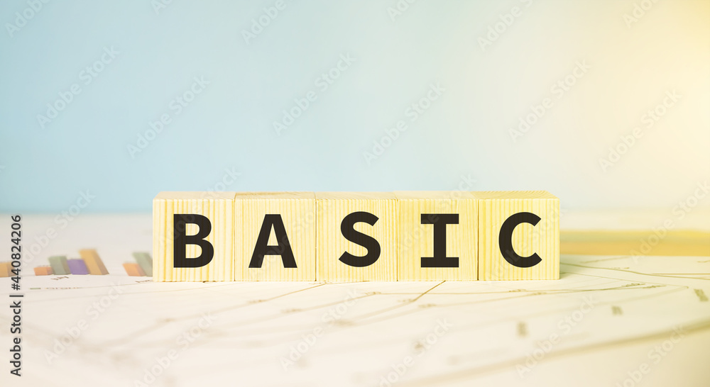 Wooden cubes with word BASIC on the office desk. Finacial reports and ...