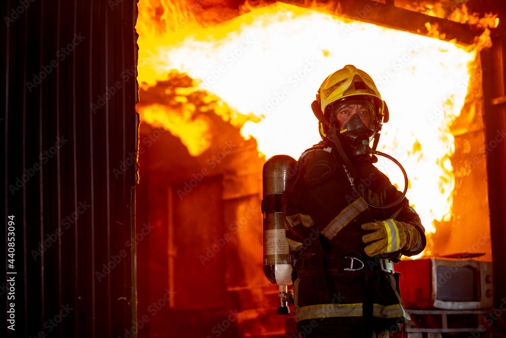 Fire on wall and ceiling in the kitchen behind firefighter man with ...