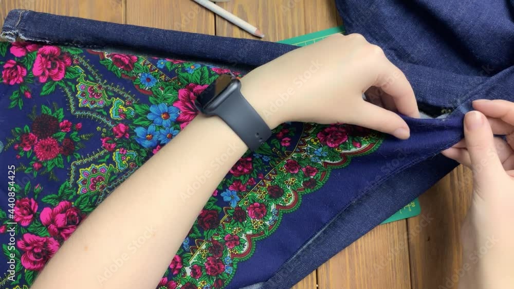 Women's hands apply patterned handkerchief to jeans that are split ...