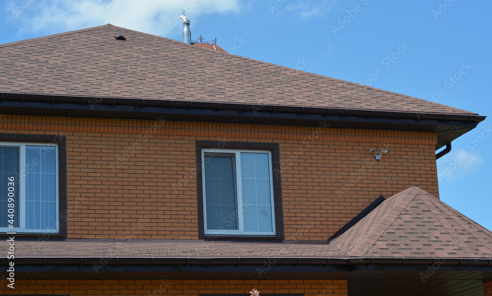 A close-up of a house with an asphalt shingled roofing construction, a ...