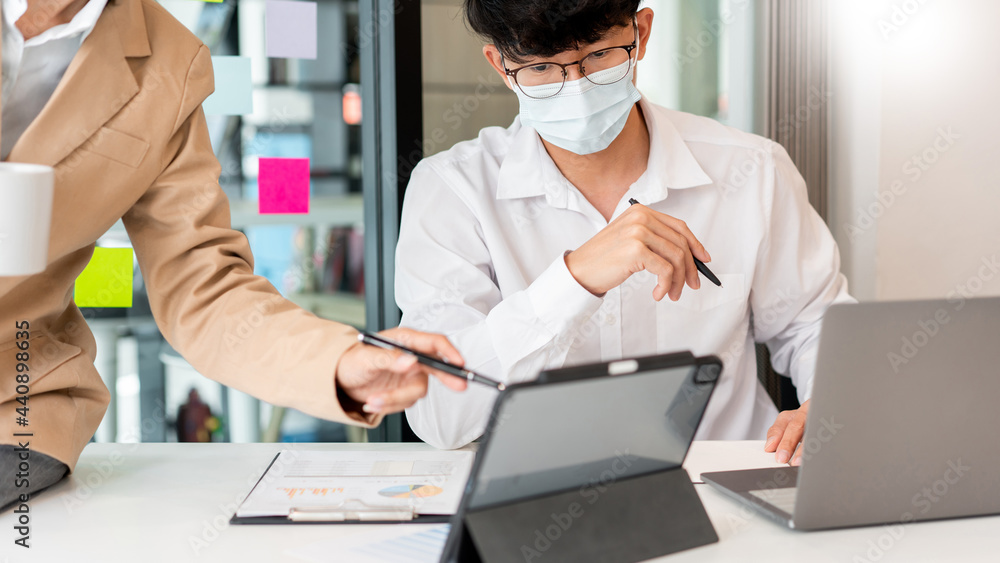 Two colleagues wearing surgical masks analyzing the data in chart for ...