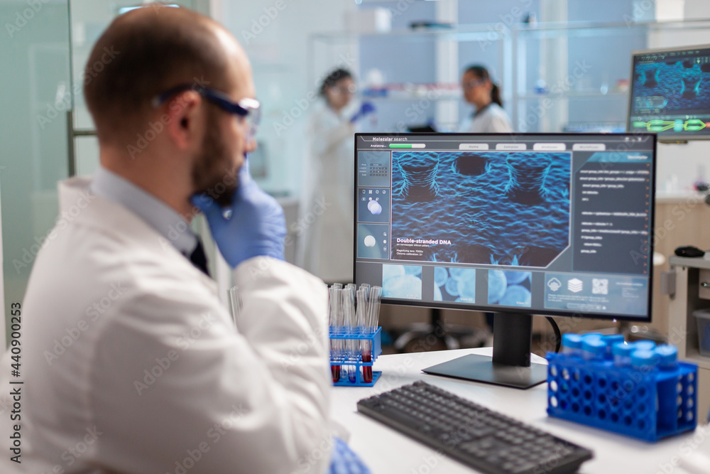 Thoughtfull doctor analyzing virus evolution on computer screen wearing ...