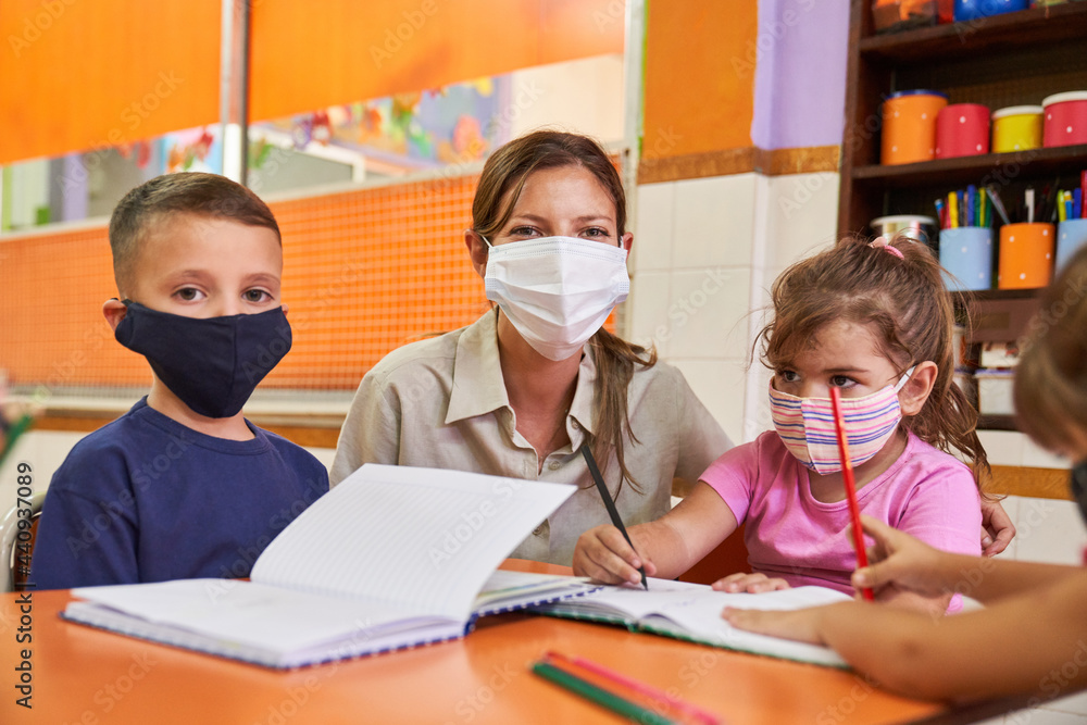 Kindergarten teacher and children with face masks because of Covid-19 ...