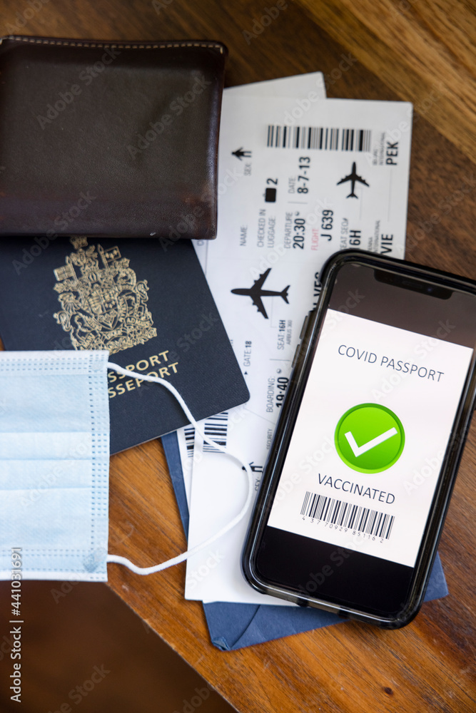 Face mask, passport, airplane ticket and covid passport on smart phone ...