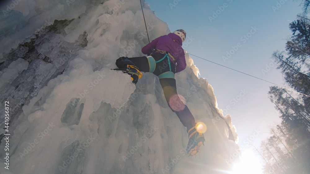 Female ice climber in triangle-shaped form pulling the top safety rope ...
