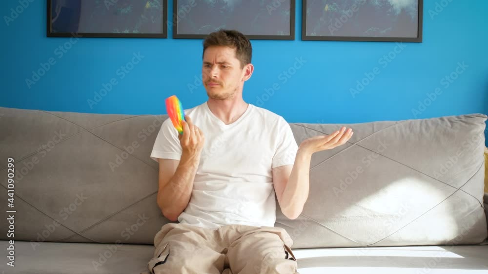 What is pop it or simple dimple. A man sits on the couch picks up pop ...