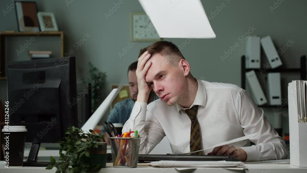 Tired irritated man working in office, angry employee having headache ...
