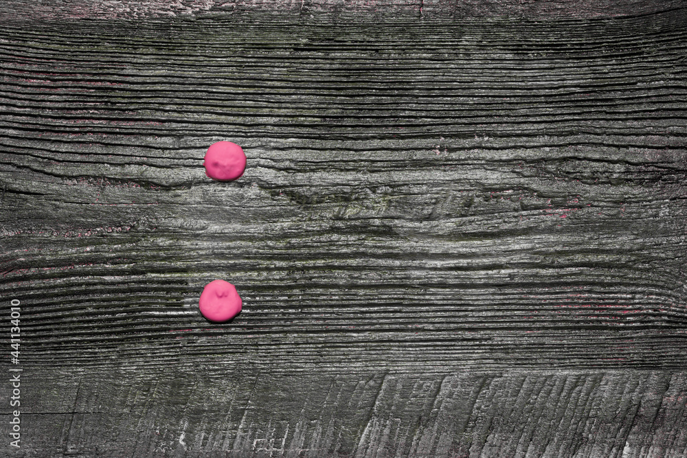 Two pink dots, painted with squeezed paint from a tube on an old wooden ...