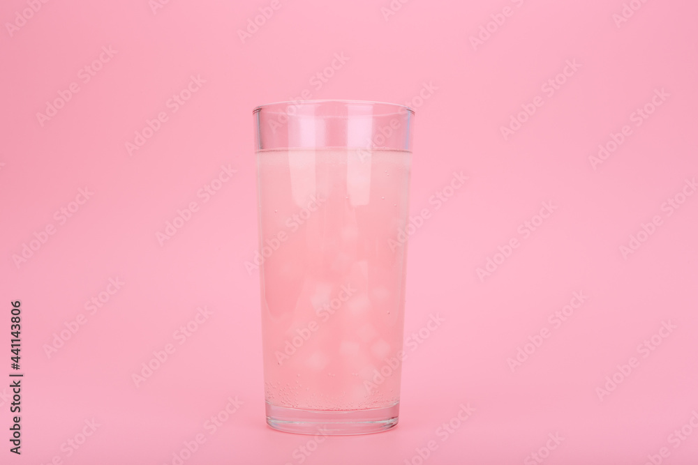 Close up of transparent glass with light pink fruit drink or lemonade ...