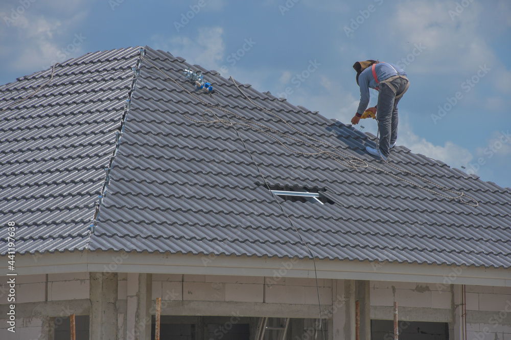 A construction worker wearing a full body safety belt is installing ...