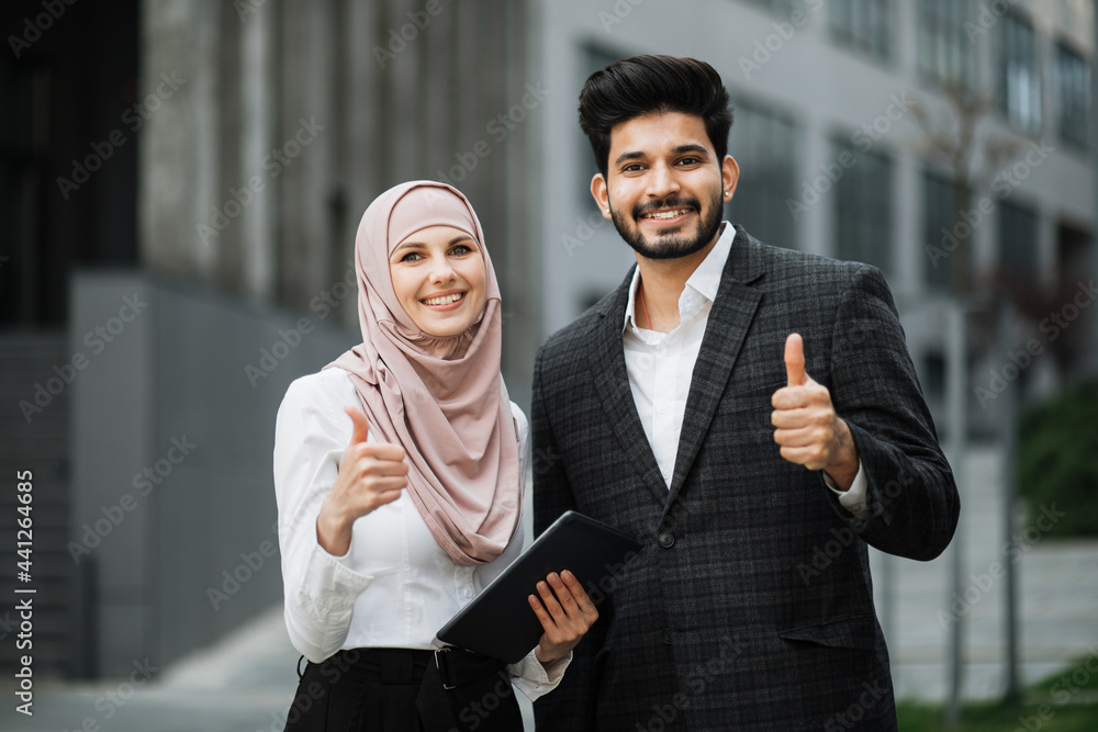 Smiling woman in hijab and muslim handsome man showing thumbs up while ...