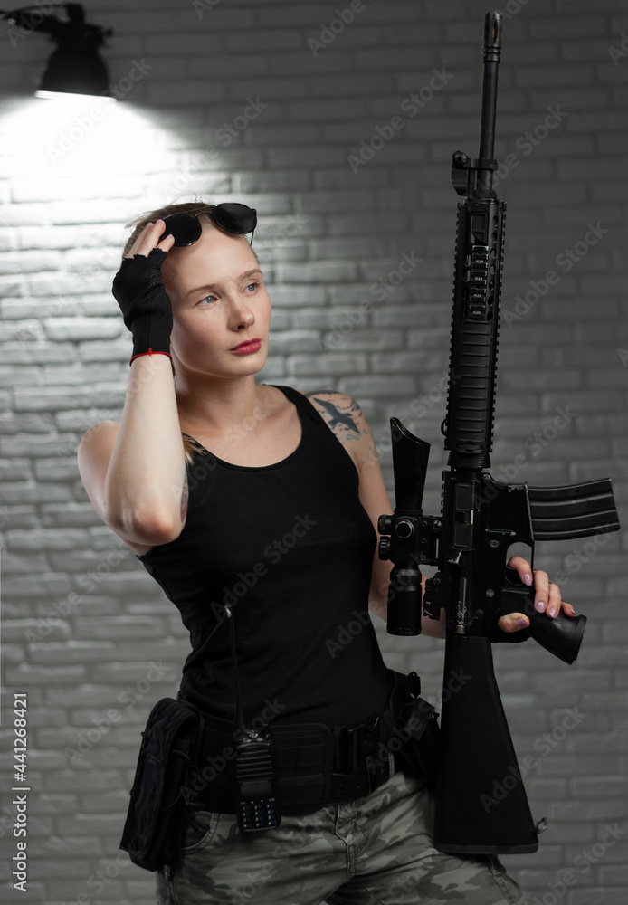 Foto de a young female soldier poses with an automatic rifle with a ...