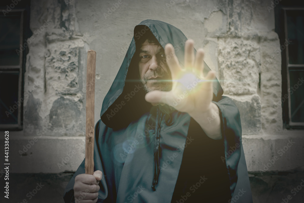 Radiance and power emanates from the hand of an elderly monk in a black ...
