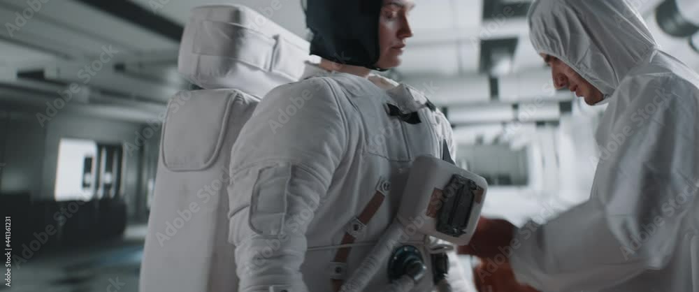 Crew member performing pre-flight inspection on a female astronaut ...