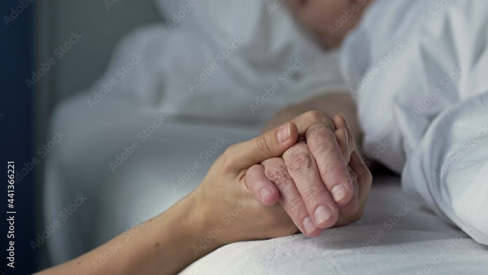 Caring young hand holding the hand of an old and sick loved one. Love ...