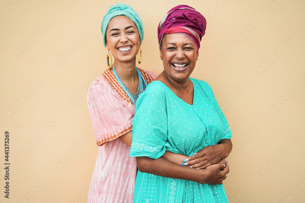 Happy african mother and daughter hugging each other while wearing traditional dresses - Focus ...