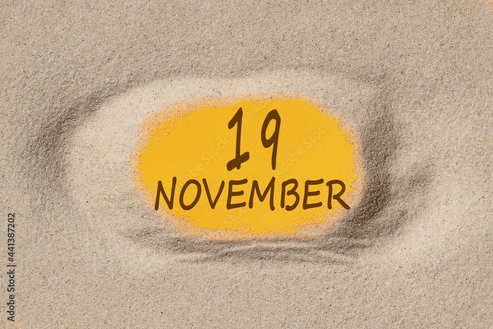 November 19. 19th day of the month, calendar date. Hole in sand. Yellow ...