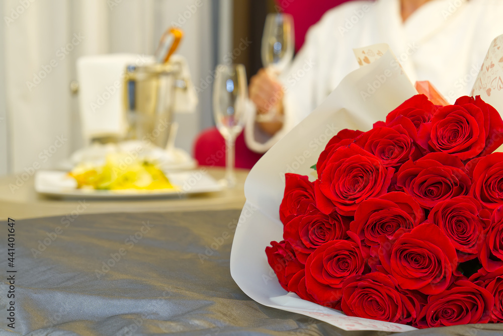 Bouquet of red roses on the bed in a hotel room. Romantic meeting of ...