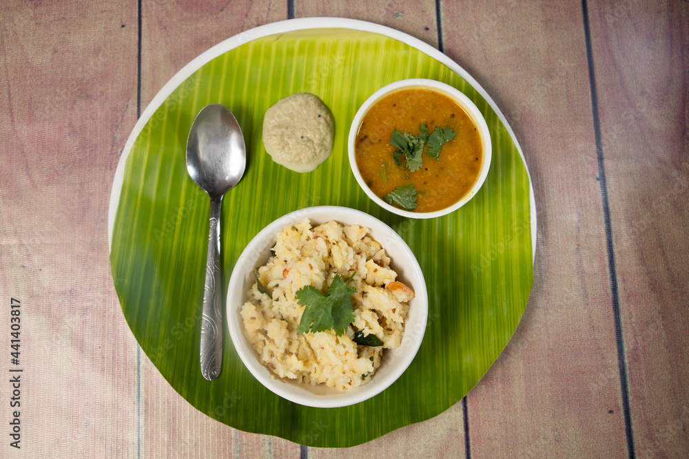 top view of Ven pongal on banana leaf with sambar and coconut chutney ...