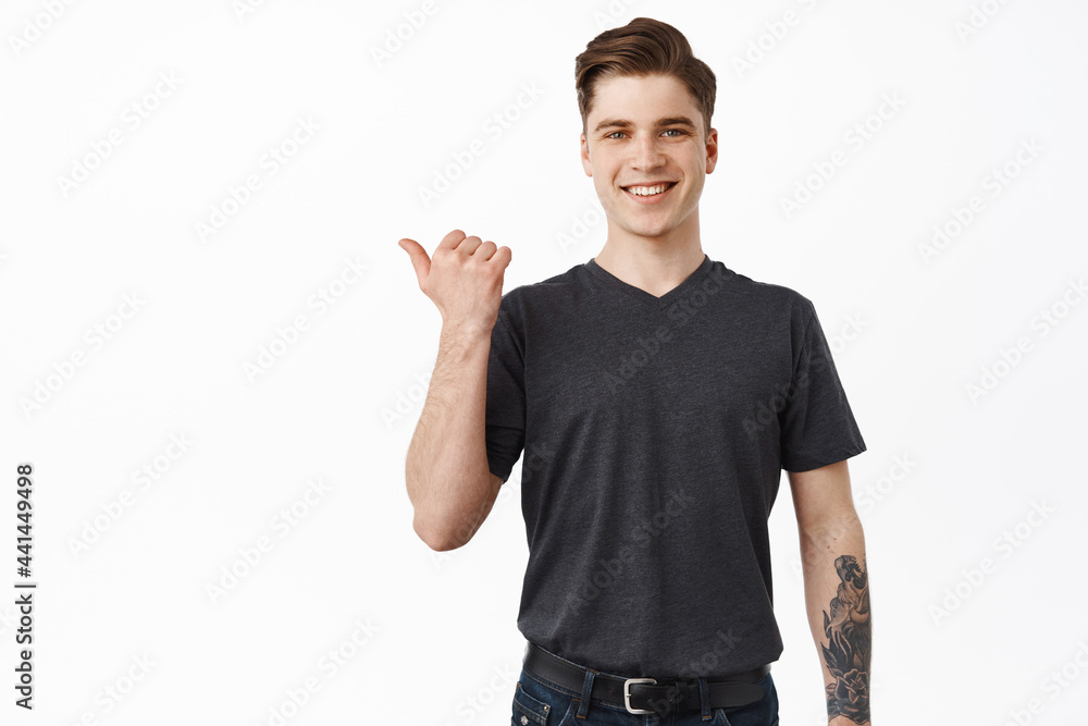 Handsome smiling man pointing left. Confident young guy student showing ...