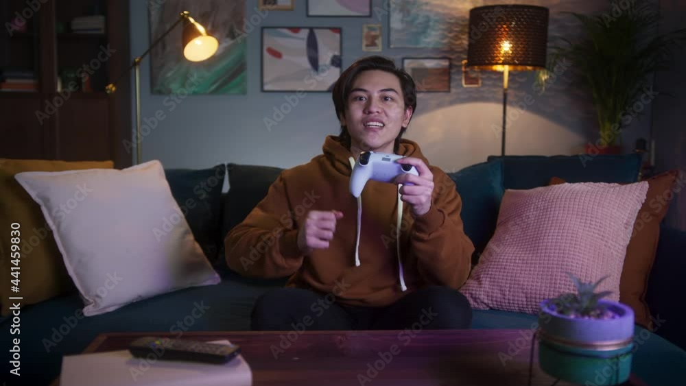 Vidéo Stock Excited Asian teenager man playing video games on modern ...