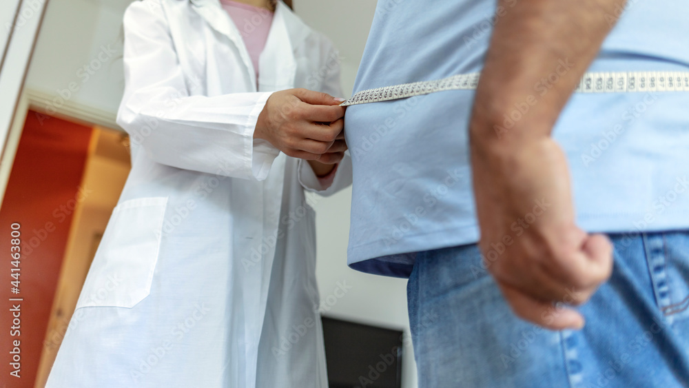 A nutritionist doctor measures the body of a male patient with a ...