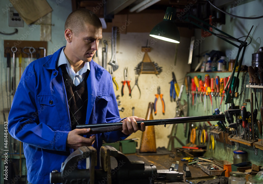 Gunsmith examines and checks double-barreled hunting rifle in a weapons ...
