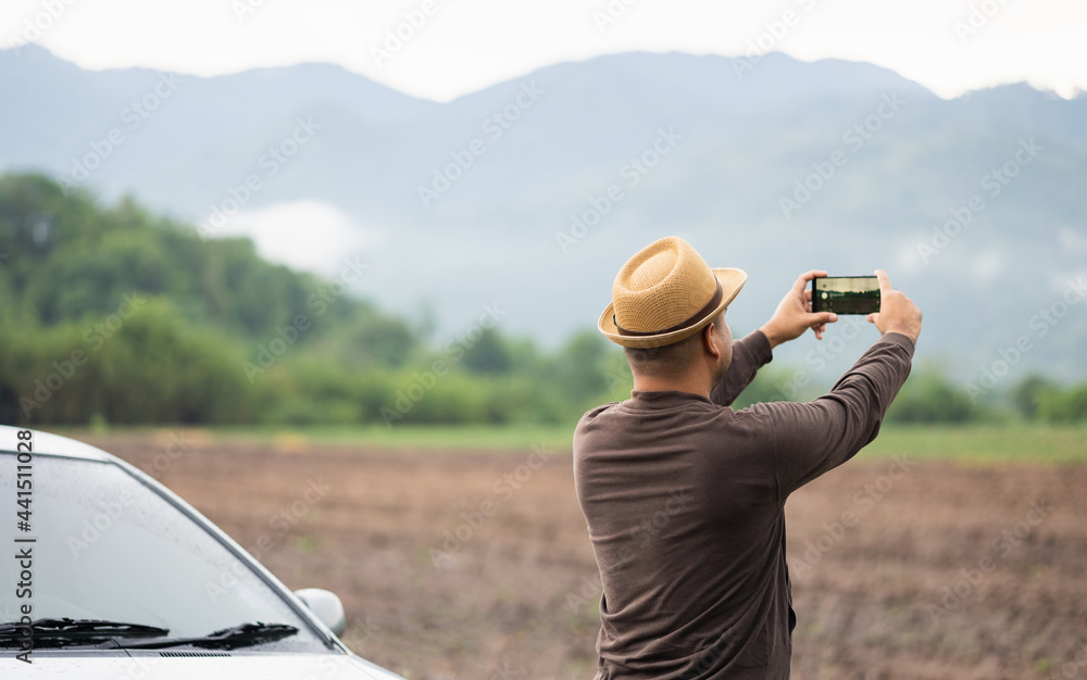 A young Asian man drives a beautiful nature drive. He was standing in ...