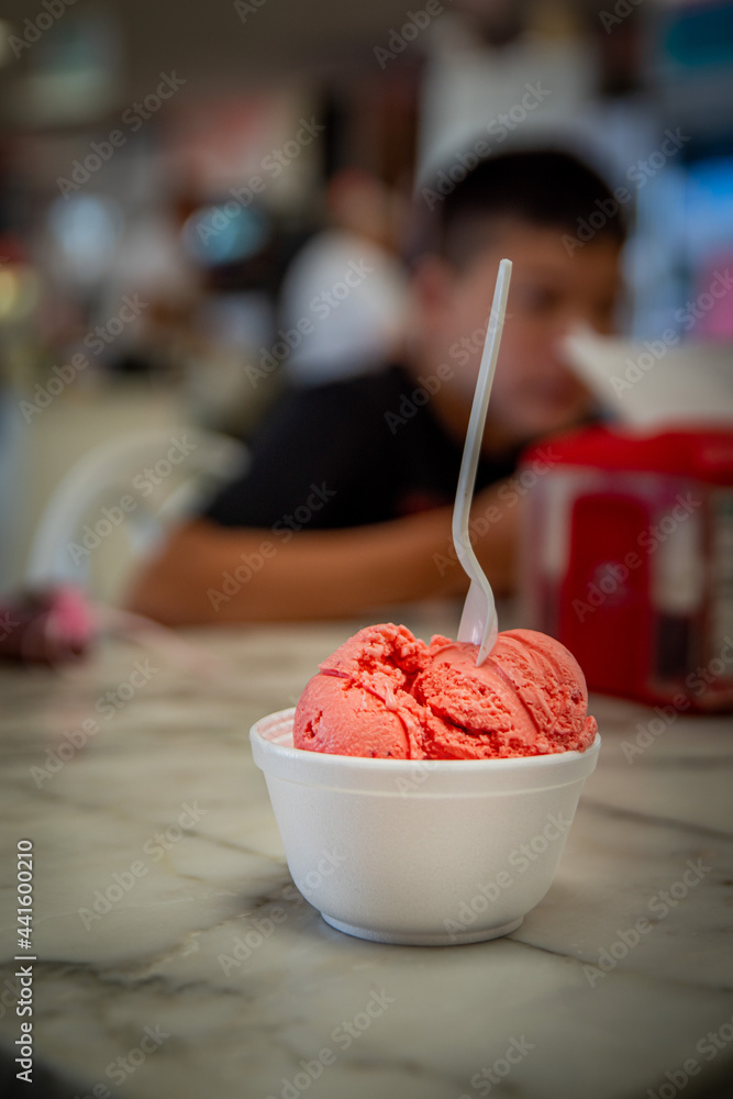 White plastic polystyrene bowl of strawberry ice cream with single-use ...