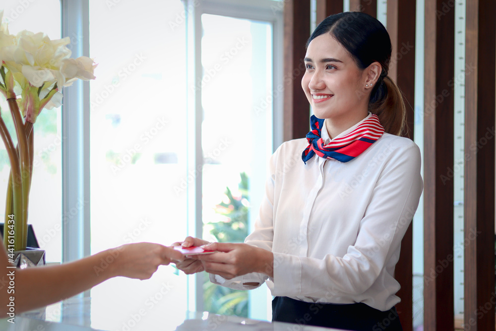 Smiling young beautiful Asian female receptionist giving key card to ...