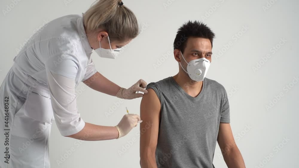 Caucasian young man receiving vaccine against coronavirus during mass ...