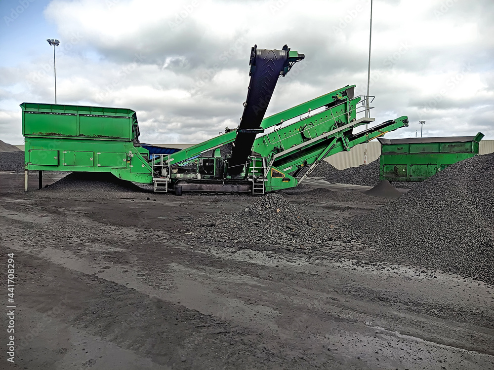 Mechanized loading of bulk cargo. Heaps of gravel on the dock and a ...