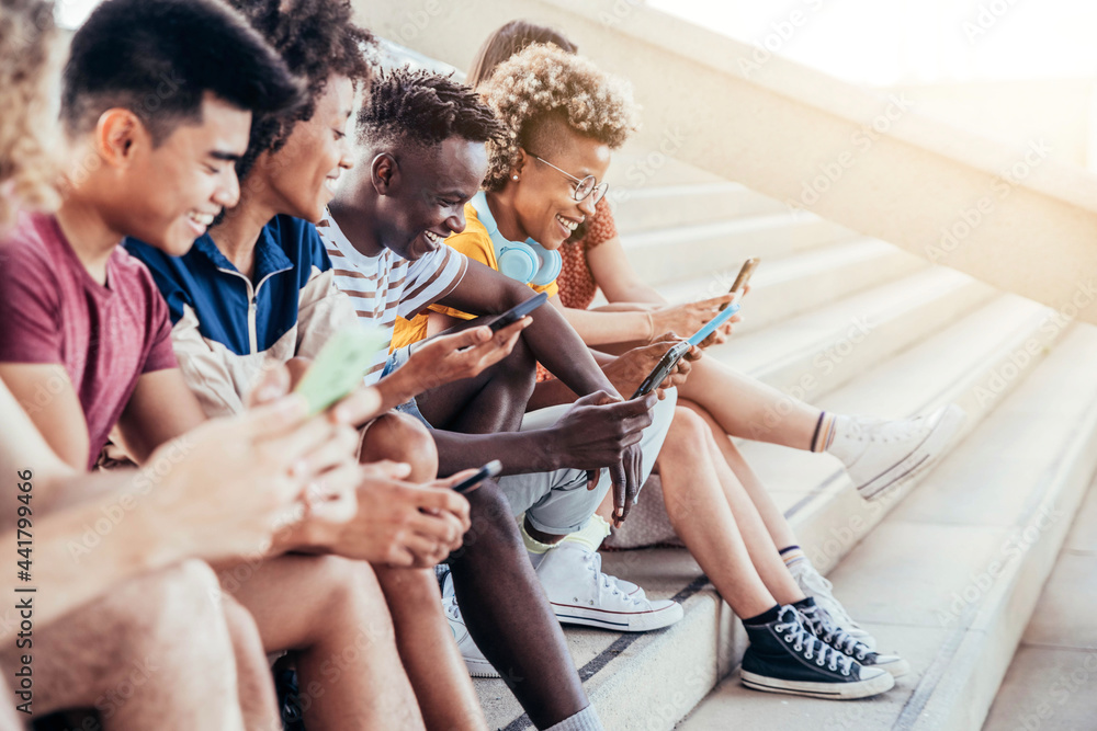 Diverse teenage students using digital smart mobile phones on college ...