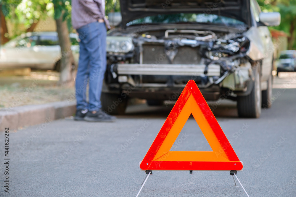 Red triangle warning sign of car accident on road in front of wrecked ...