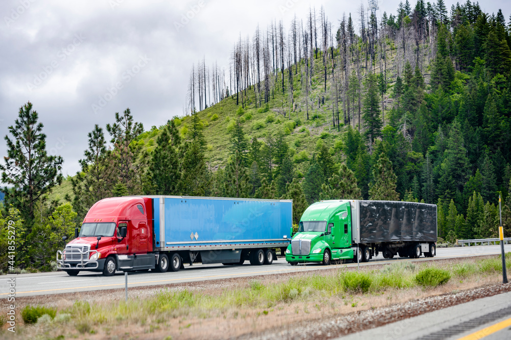 Team of two big rig semi trucks with semi trailers carry cargo driving ...