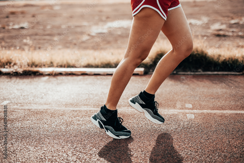 Feet of a female runner who is stepping on the running field with ...