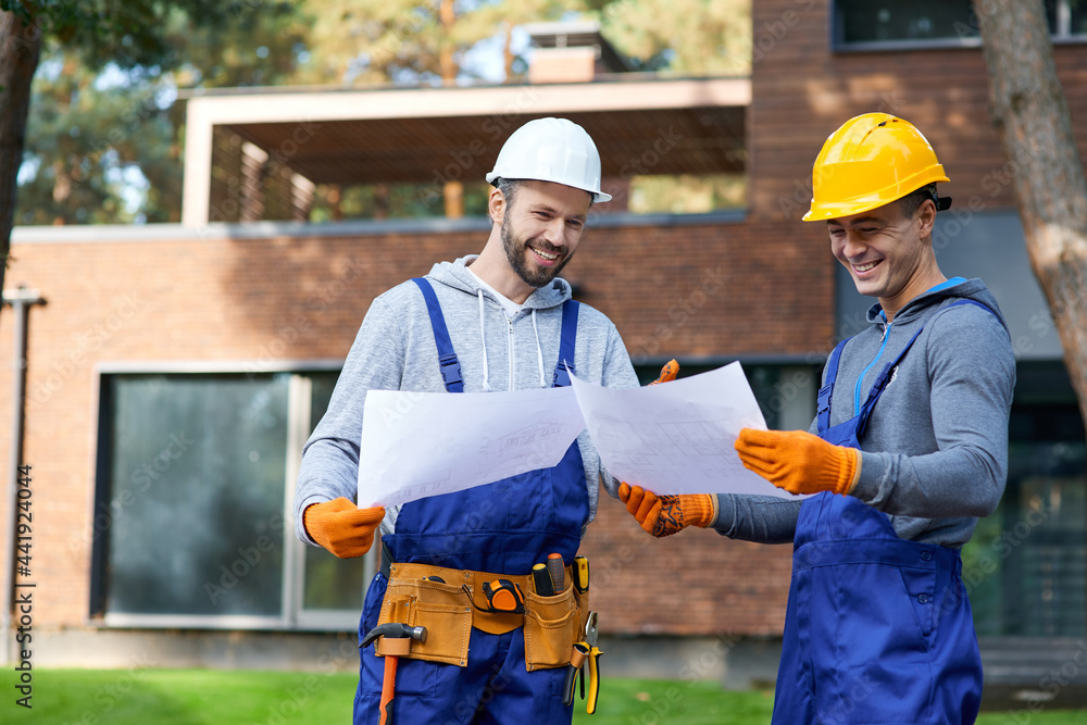 Decision making. Two positive builders smiling while standing outdoors ...