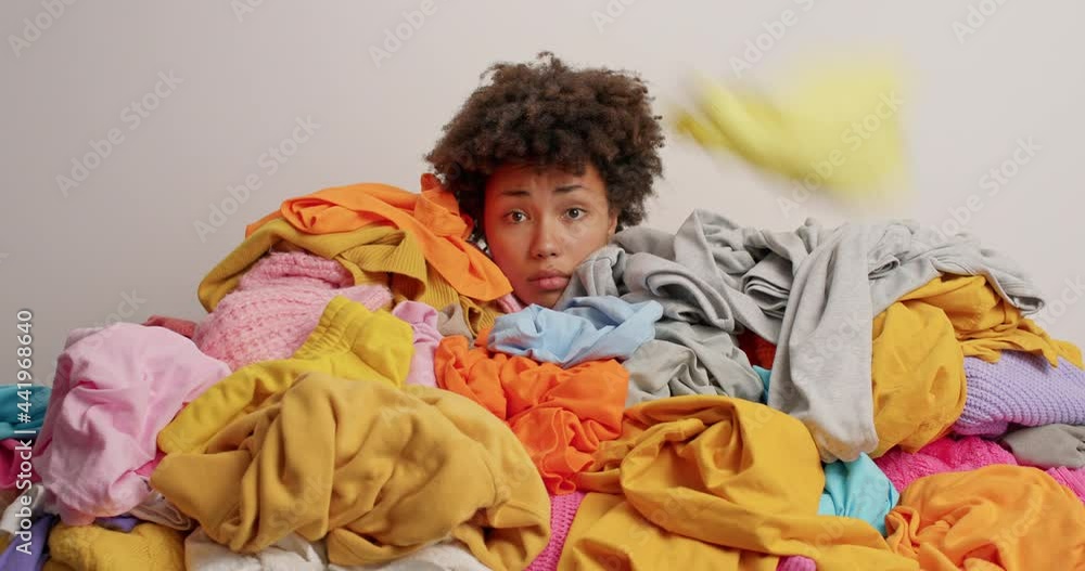 Unhappy curly haired Afro American woman with falling laundry on head ...