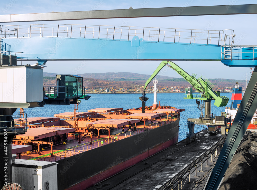 A manipulator crane in the seaport is used for unloading wagons and ...