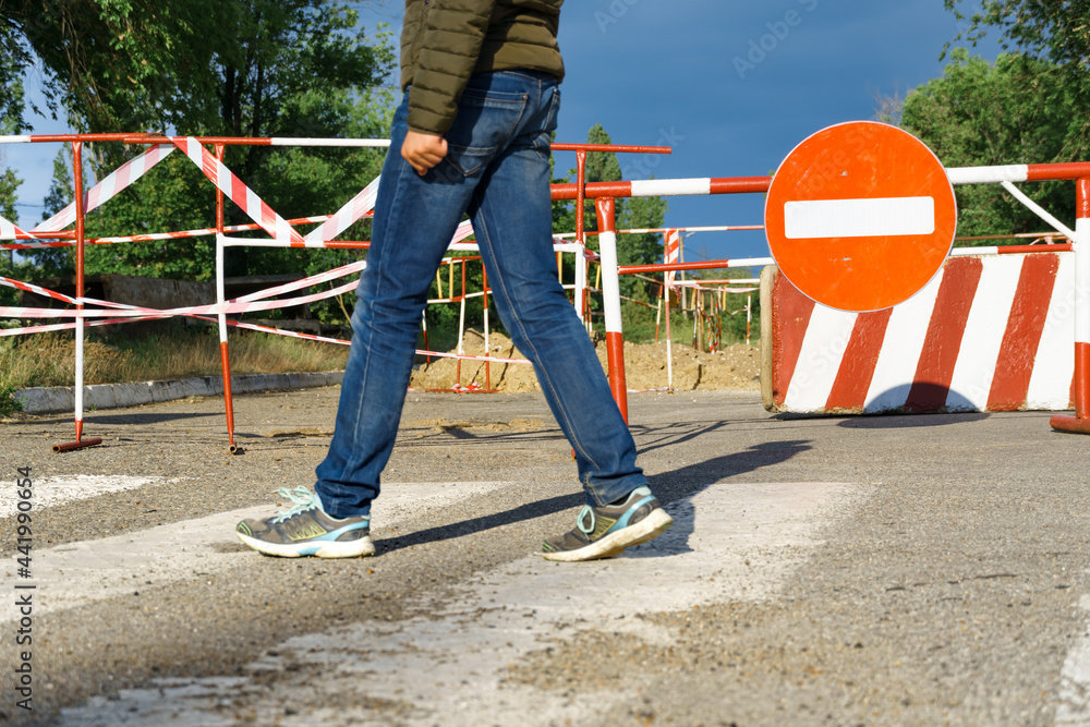 a pedestrian walks along a pedestrian crossing next to the road sign ...