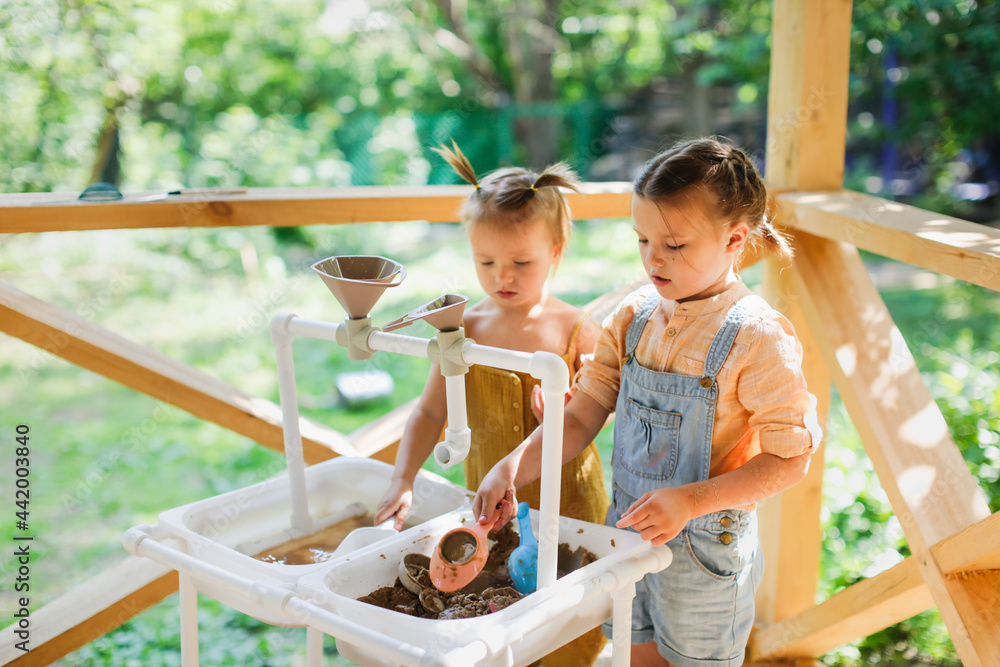 Foto de Happy sister kids play with sand and water in sensory baskets ...