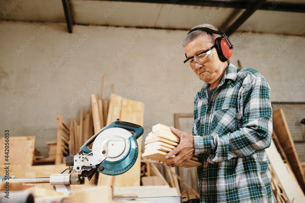Professional carpenter bringing stack of wooden planks to workbench to ...