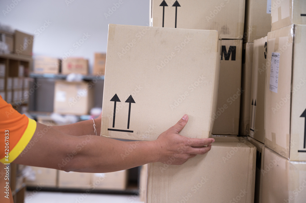 Close up hands of warehouse worker lifting box in storage room.Man ...