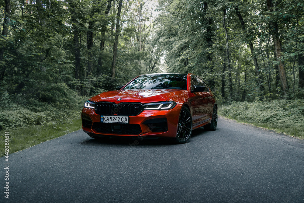 New BMW M5 F90 LCI Competition in a red color on the forest road. Kyiv, Ukraine - June 2021 ...