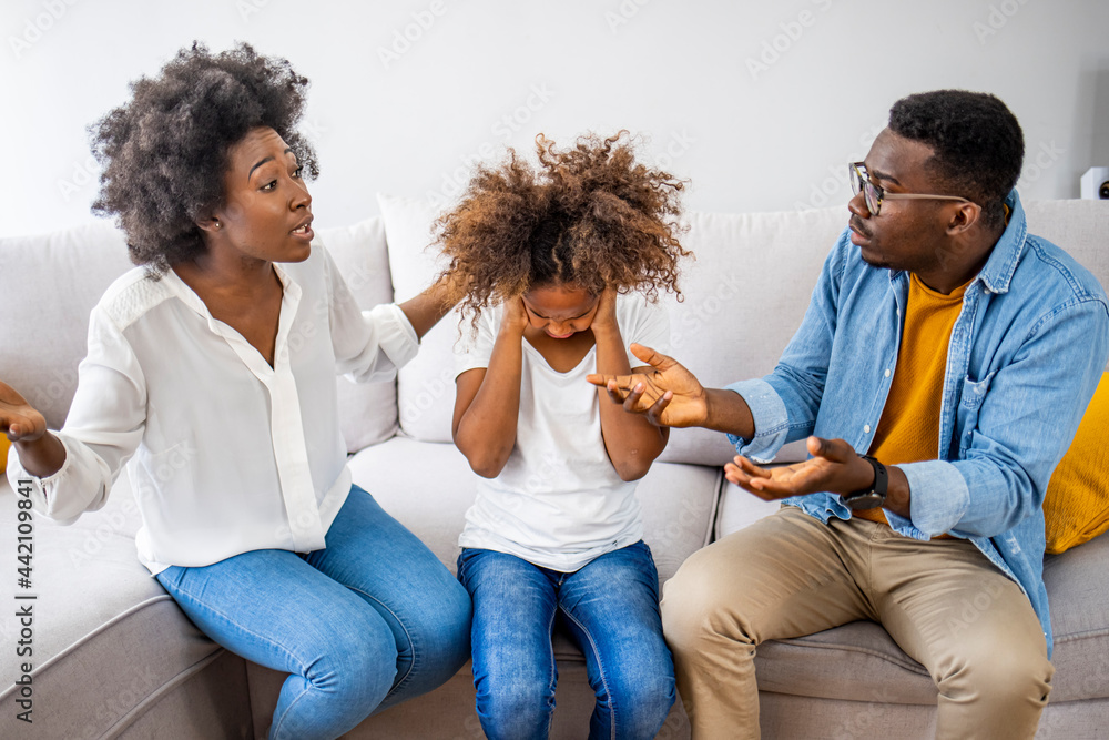Sad little girl is looking at camera while her parents are arguing in ...